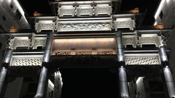 Um portão tradicional chinês com esculturas detalhadas e uma placa com caracteres chineses.