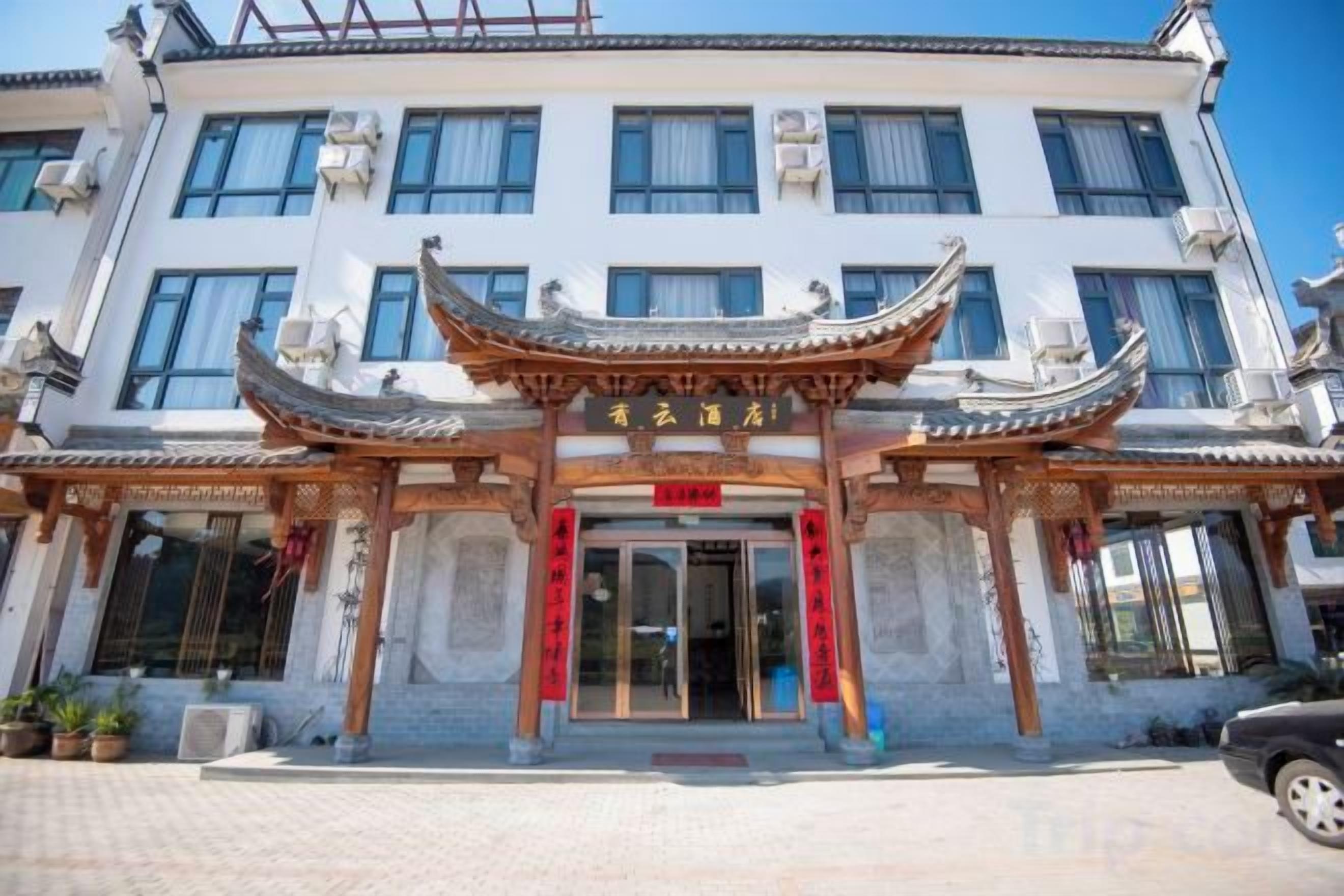 Um edifício com entrada de arquitetura tradicional chinesa, várias janelas e céu claro.