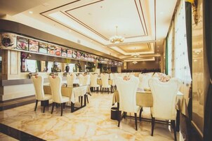 Restaurante com chão de mármore, cadeiras brancas e um cardápio em exposição.