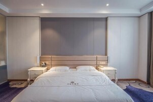 Quarto de hotel com uma cama grande, duas mesas de cabeceira, cabeceira e piso coberto por carpete.