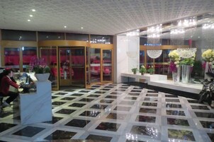 Um saguão com balcão de atendimento, área de recepção e um arranjo floral decorativo.