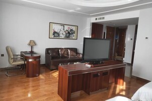 Uma sala de estar com televisão, sofá, poltrona e mesa de centro.