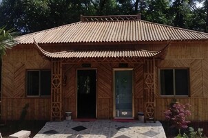 Uma casa de bambu com entrada coberta de azulejos e telhado de metal.