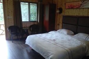 Quarto de madeira com uma cama, duas cadeiras, uma mesa pequena e uma janela.