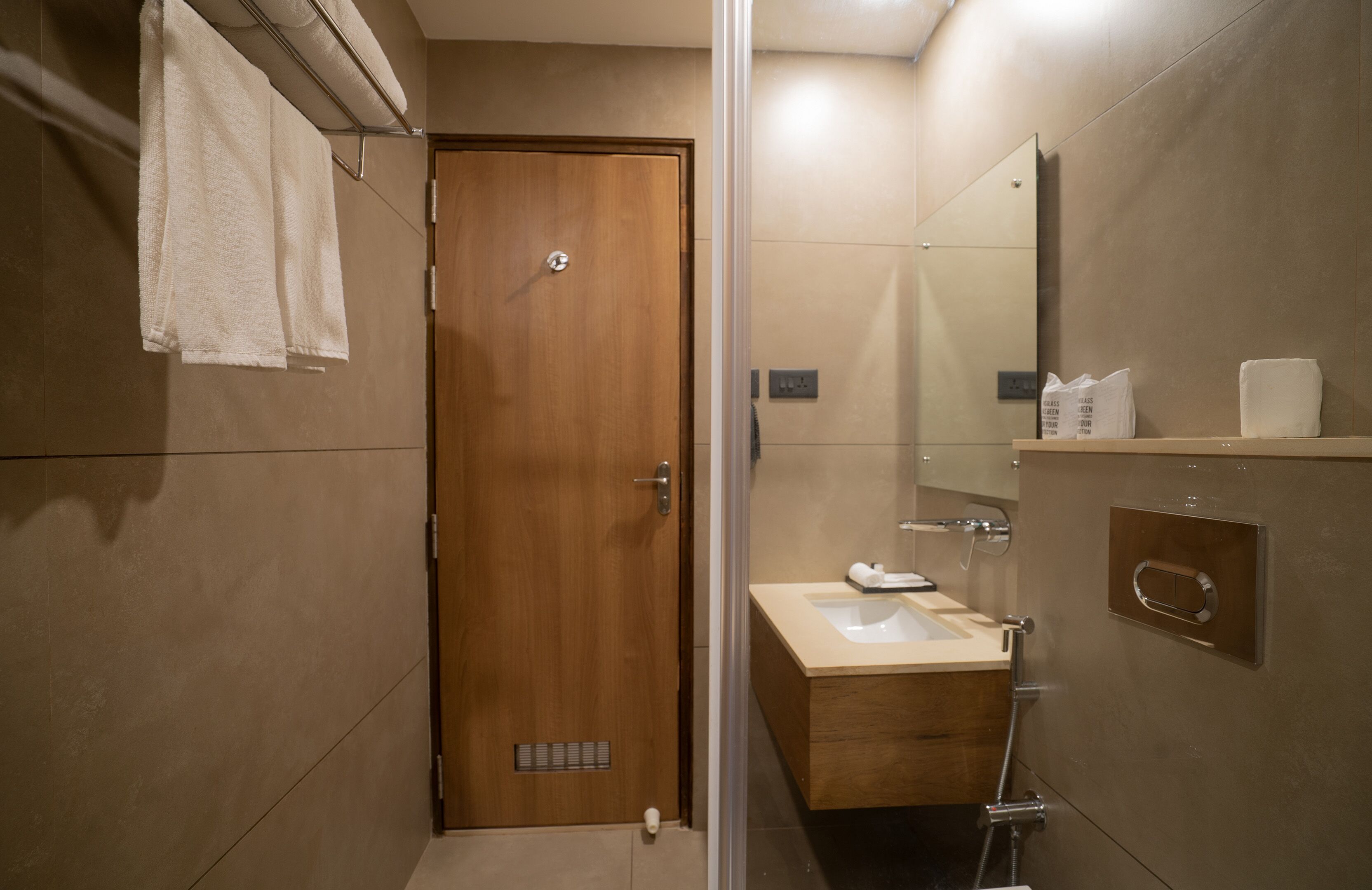 Um banheiro moderno com porta de madeira, pia e espelho.