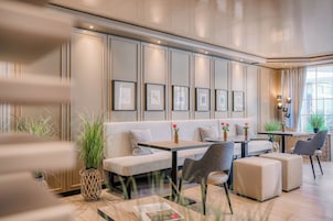 Uma área de estar moderna com um sofá, cadeiras, uma mesa e quadros na parede.