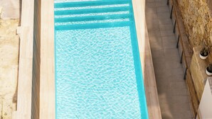 Piscina com água cristalina e área do deck revestida em azulejos.