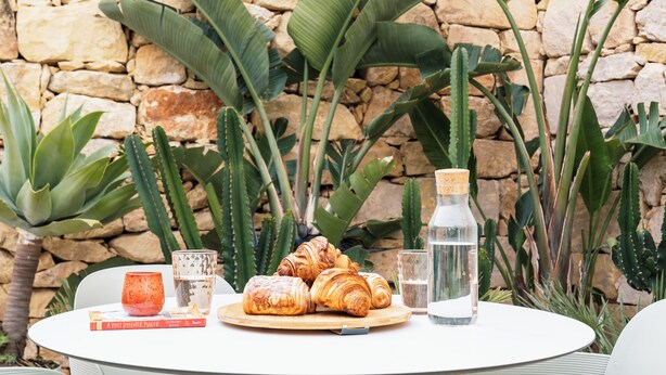 Uma mesa com croissants, um livro e uma garrafa de água.