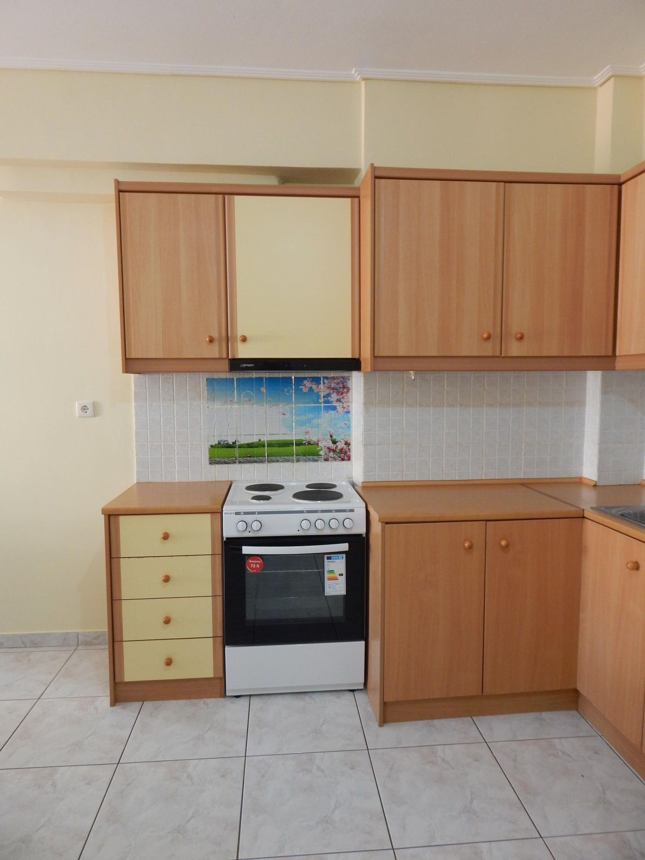 Uma cozinha compacta com armários de madeira, fogão embutido e painel de azulejos.