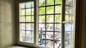 Quarto com grandes janelas com vista para uma movimentada área de mercado ao ar livre.