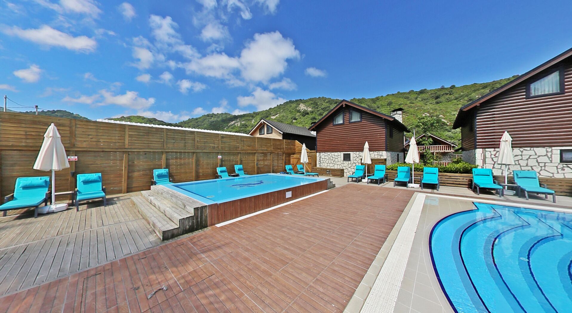 Um resort com piscina, espreguiçadeiras e cabanas de madeira.