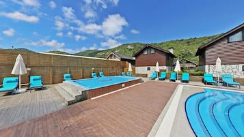 Um resort com piscina, espreguiçadeiras e cabanas de madeira.