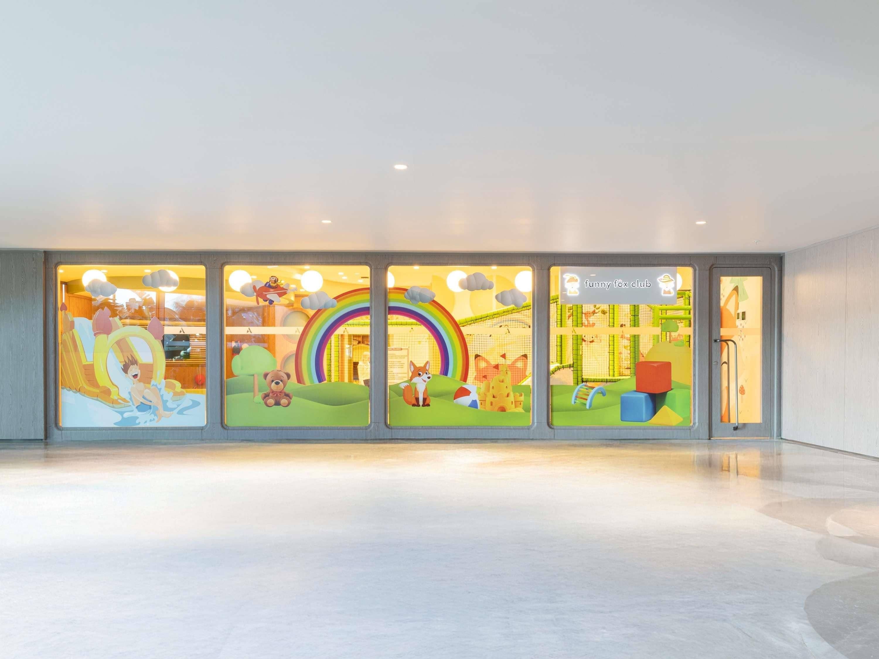 Espaço de recreação infantil com murais coloridos e um letreiro 'funny fox club'.