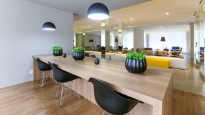 Cozinha moderna com bancada de madeira, cadeiras pretas e plantas em vasos.