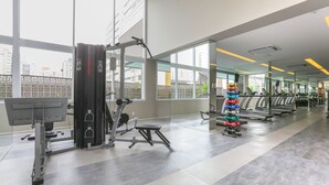 Uma academia com equipamentos de exercícios, esteiras e janelas amplas.