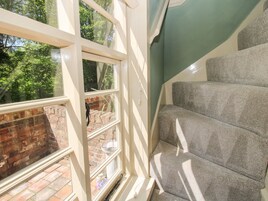 Quarto com janela que dá para uma parede de tijolos e vegetação.