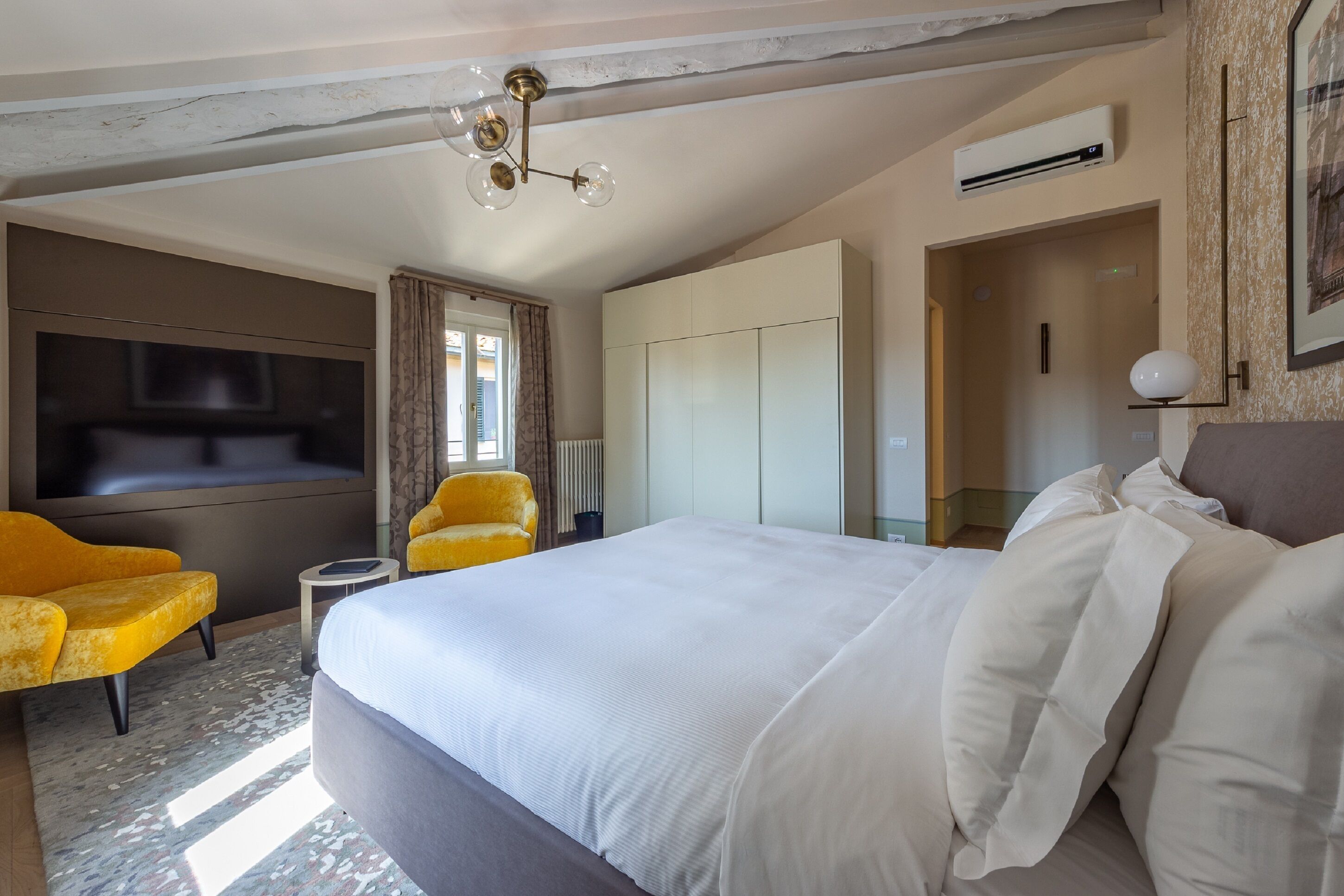 Quarto de hotel com uma cama grande, televisão, sofá e guarda-roupa.
