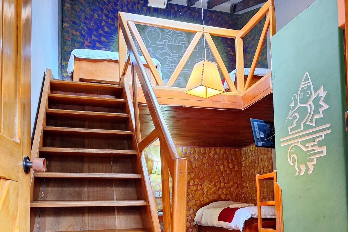 Escada de madeira que leva a uma cama beliche com luminária pendente.
