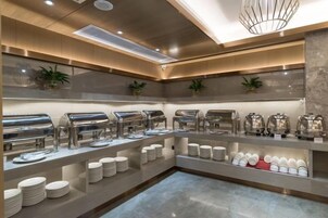 Disposição de buffet com vários estações de serviço, incluindo opções de comida quente e fria, e uma variedade de pratos para servir.