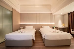 Quarto de hotel com duas camas de solteiro, uma mesinha de cabeceira e uma cadeira.