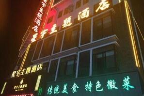 Edifício com sinalização iluminada indicando hotel e restaurante.