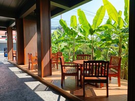 Espaço ao ar livre com mobiliário de madeira e grandes bananeiras.