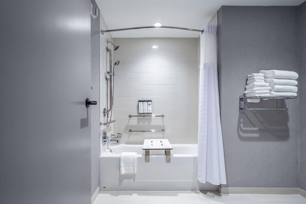 Um banheiro moderno com banheira, chuveiro e porta-toalhas.