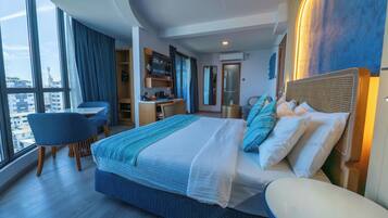 Quarto de hotel com cama, escrivaninha, cadeira e vista para a cidade.