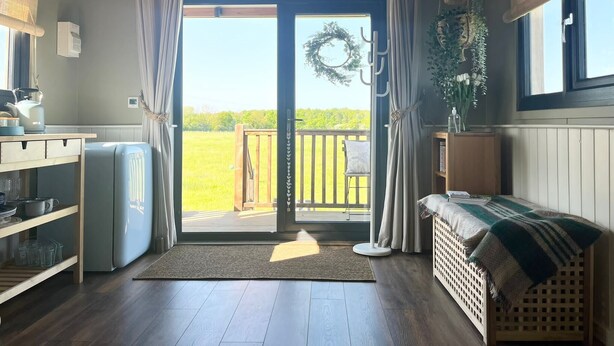 Quarto acolhedor com porta deslizante para uma varanda, cozinha compacta com frigorífico e área de estar com um banco.