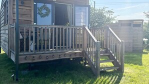 Uma cabana de madeira com varanda, porta e janela.