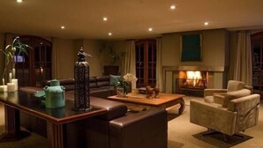 Uma sala de estar aconchegante com lareira, sofás de couro, uma mesa de centro e objetos decorativos.
