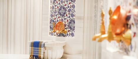 Um banheiro com uma banheira branca, uma janela com azulejos estampados e uma toalha pendurada sobre a banheira.