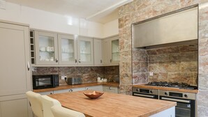 Cozinha moderna com ilha de madeira, eletrodomésticos de aço inoxidável e backsplash de mármore.