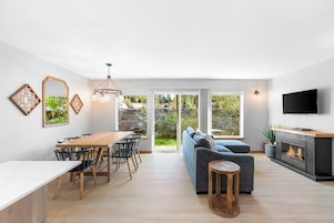 Uma sala de estar moderna com área de jantar, lareira e TV na parede.
