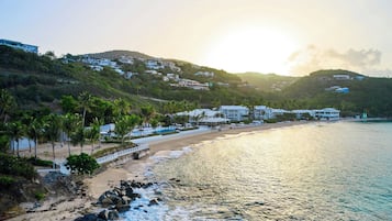 Um resort costeiro com villas na orla, uma praia de areia e um litoral rochoso.