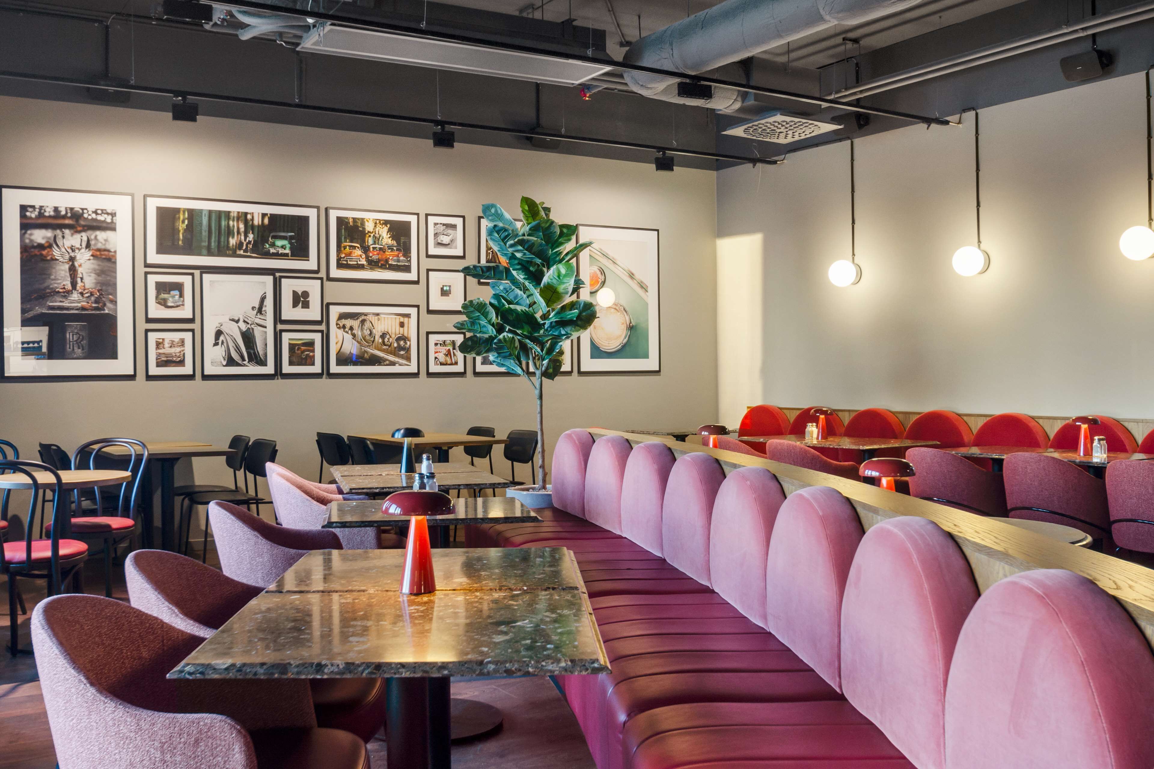 Um restaurante moderno com um balcão comprido, assentos acolchoados e obras de arte emolduradas nas paredes.