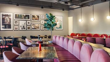 Um restaurante moderno com um balcão comprido, assentos acolchoados e obras de arte emolduradas nas paredes.