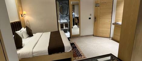 Quarto de hotel moderno com cama, mesa de centro de vidro, sofá, ventoinha no teto e guarda-roupa.