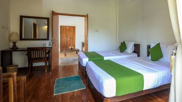 Quarto de hotel com duas camas, uma escrivaninha, uma cadeira e um espelho.