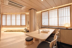 Interior moderno com mesa de jantar, cadeiras, um vaso e uma janela com vista.
