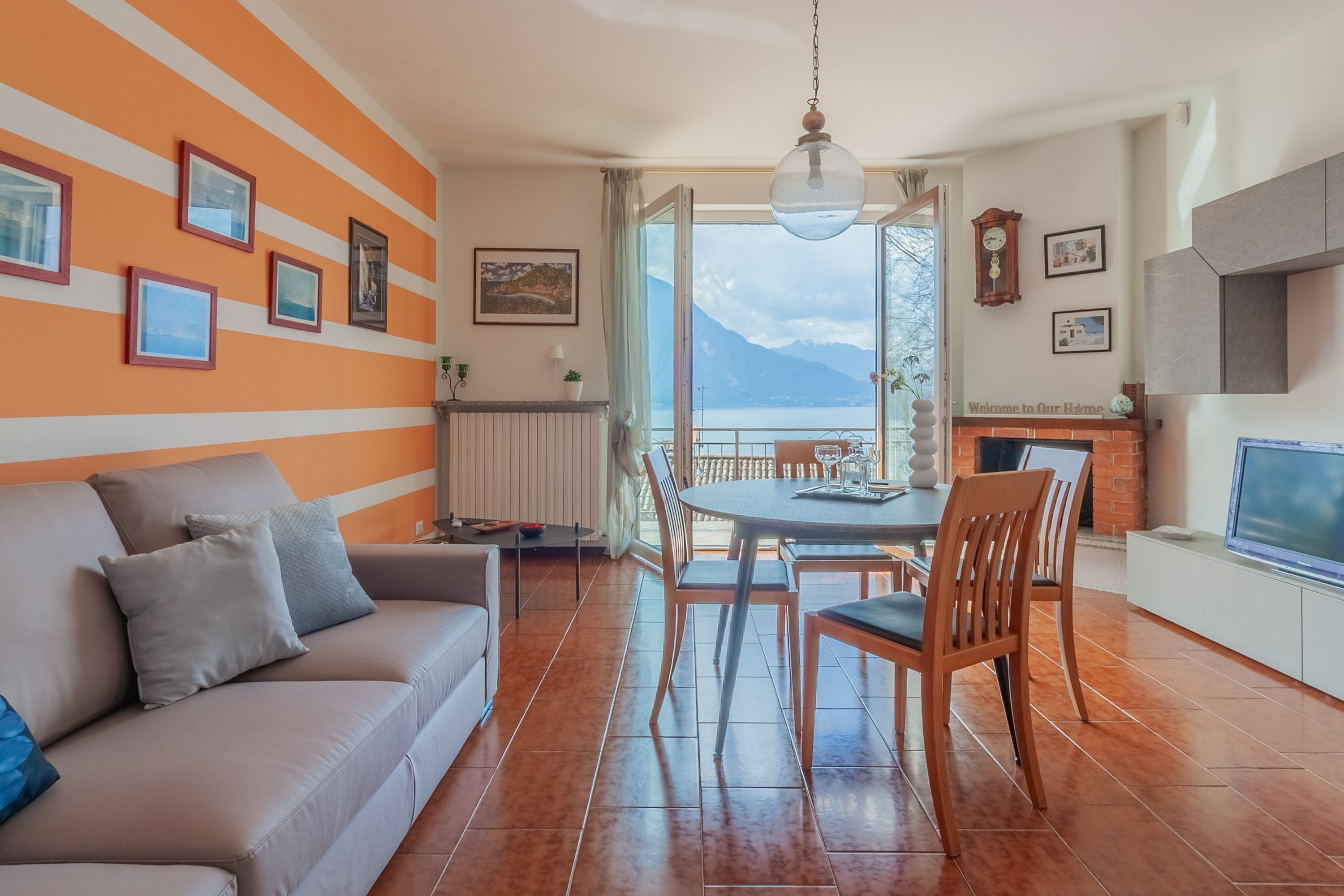 Uma sala de estar com sofá, mesa de jantar, cadeiras e lareira.