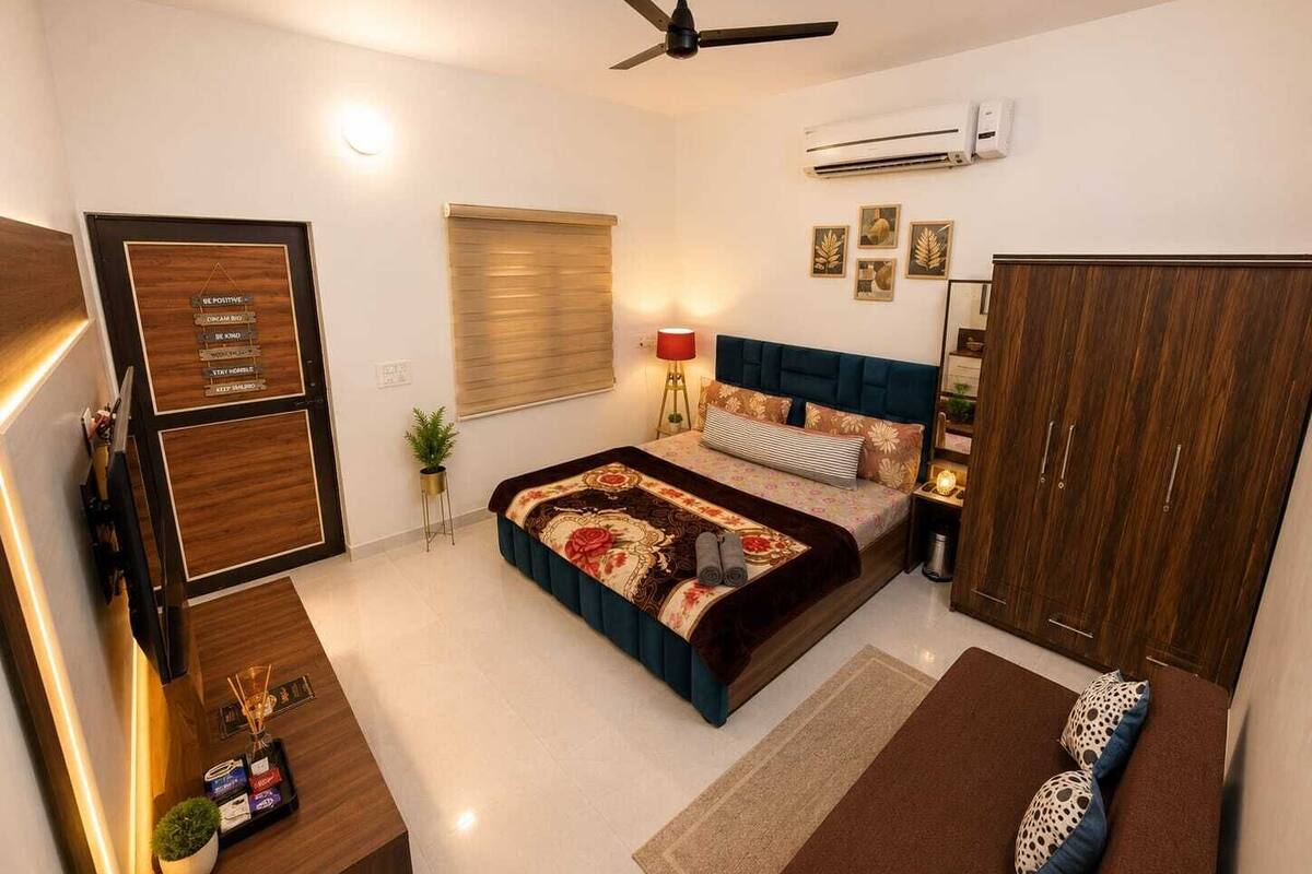 Quarto com cama, mesa de cabeceira, abajur, guarda-roupa e ar condicionado.