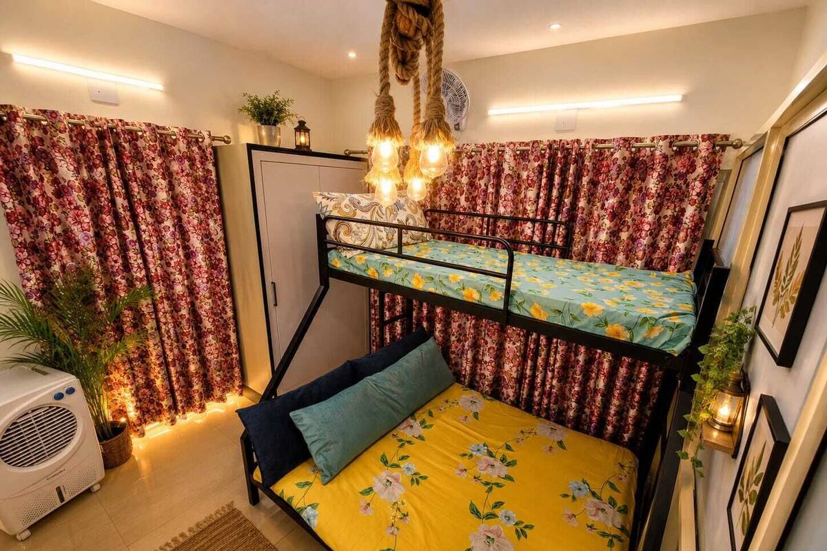 Uma cama beliche com roupa de cama florida, um ventilador portátil e um pequeno aquecedor.
