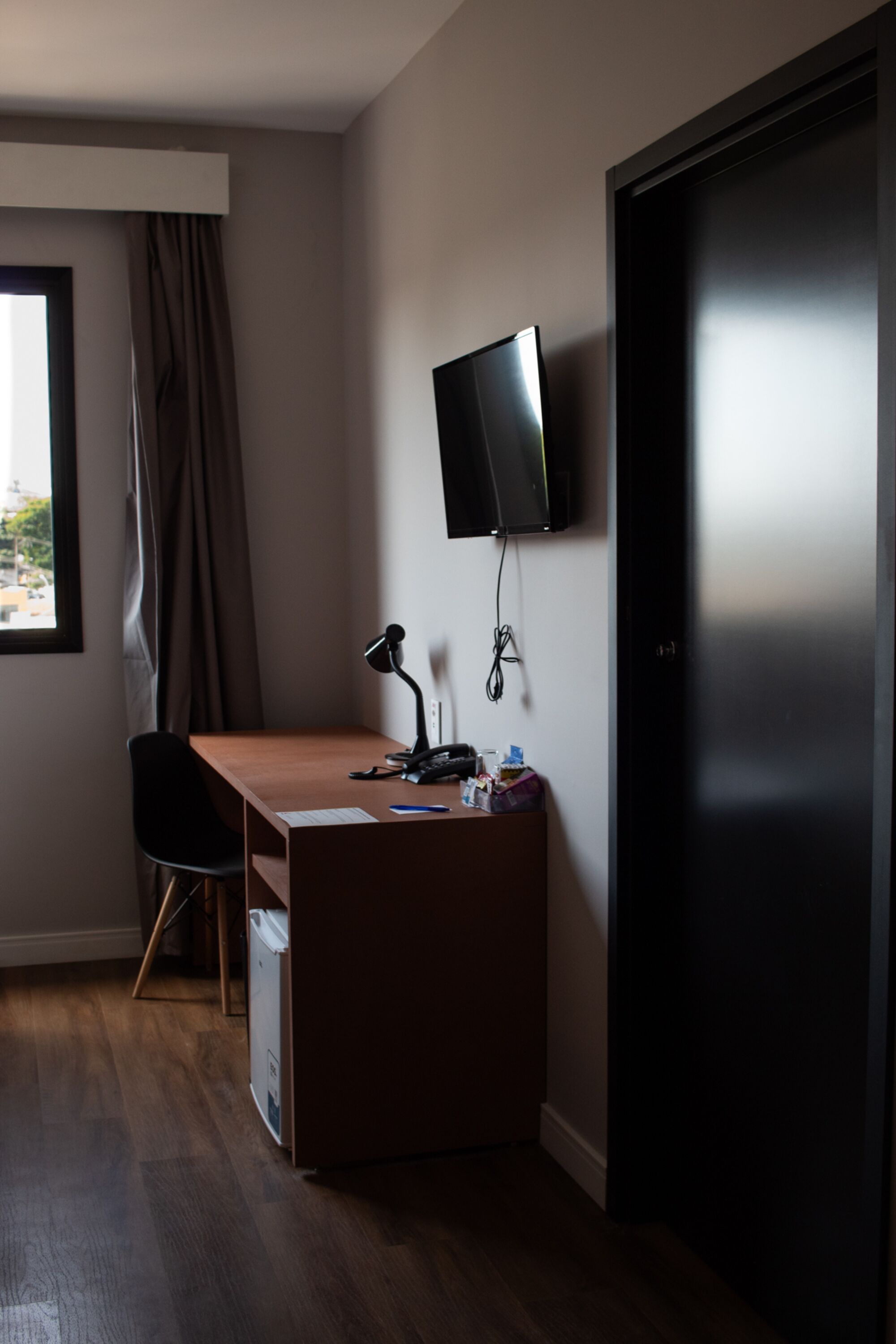 Quarto pequeno e moderno com uma escrivaninha, cadeira e televisão de tela plana na parede.