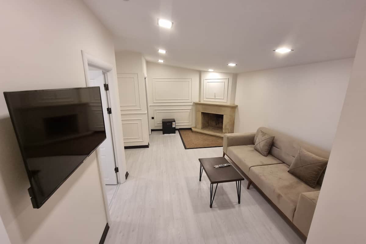 Uma sala de estar moderna com televisão de tela plana, sofá, mesa de centro e lareira.