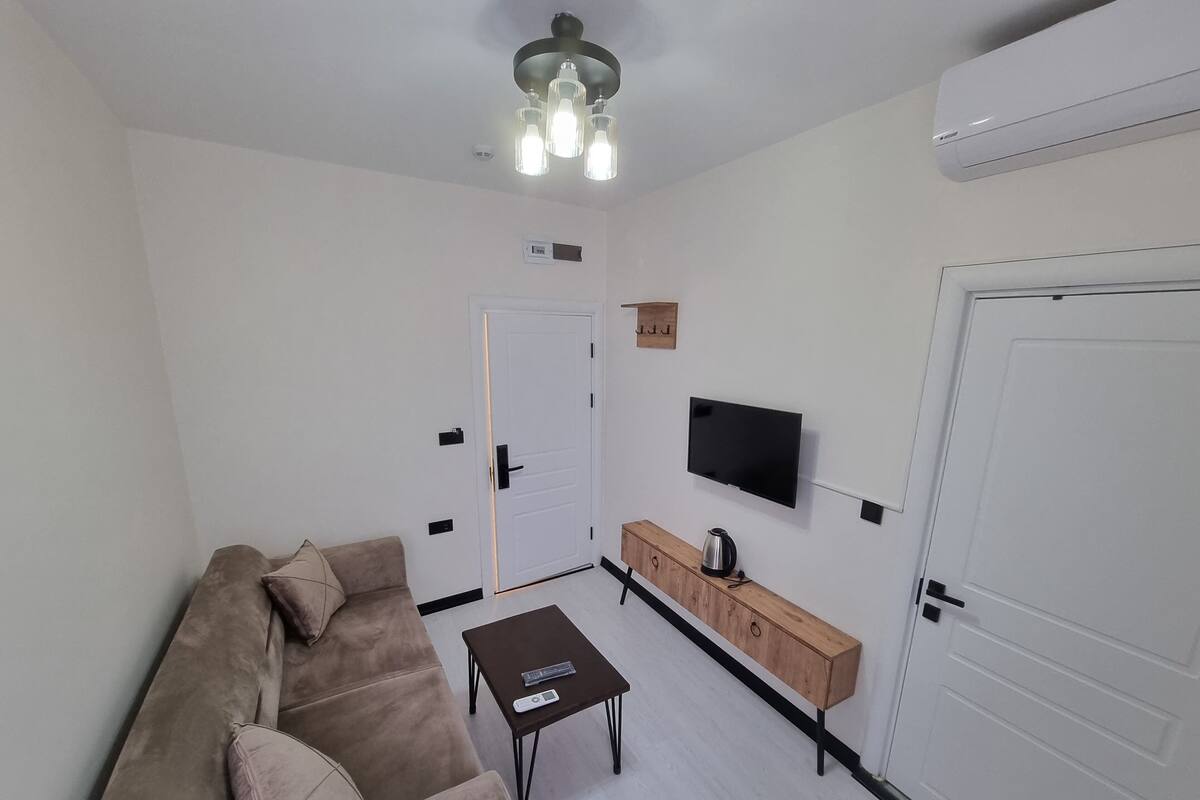 Uma sala de estar moderna com sofá, mesa de centro, televisão e armário.