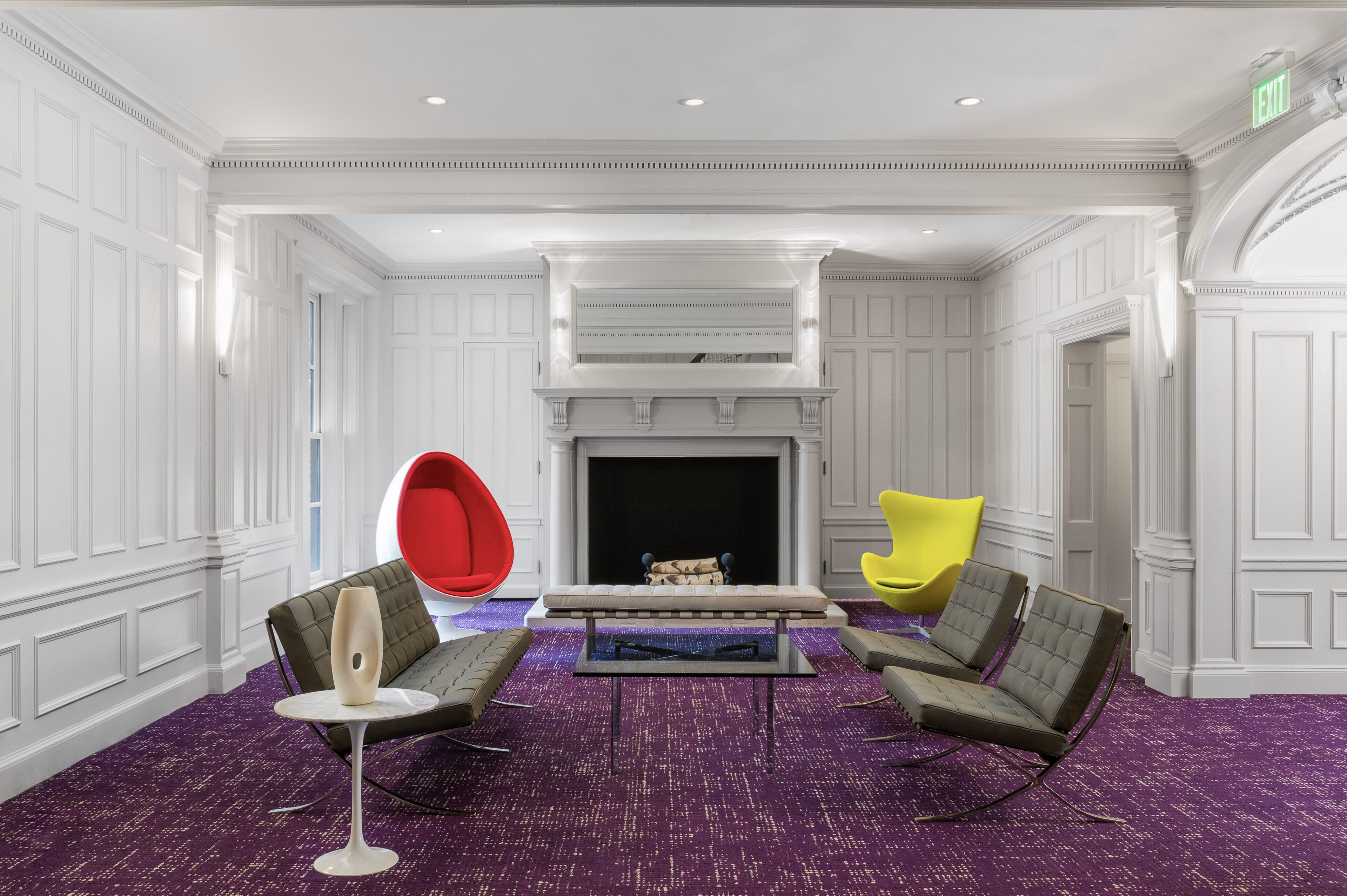 Um hall amplo com lareira, assentos modernos e tapete roxo.