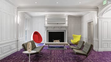 Um hall amplo com lareira, assentos modernos e tapete roxo.