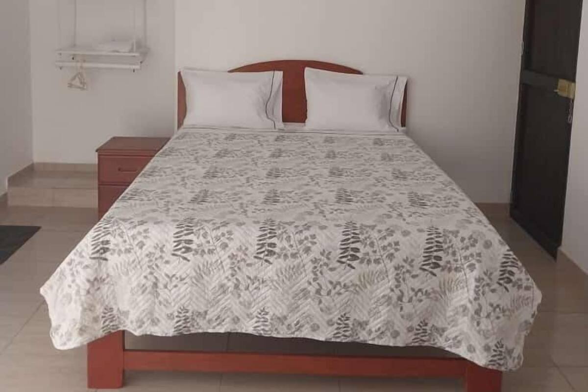 Quarto com cama, mesa de cabeceira e guarda-roupa.