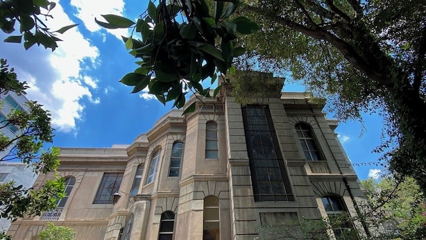 Um edifício histórico com grandes janelas e uma entrada imponente.